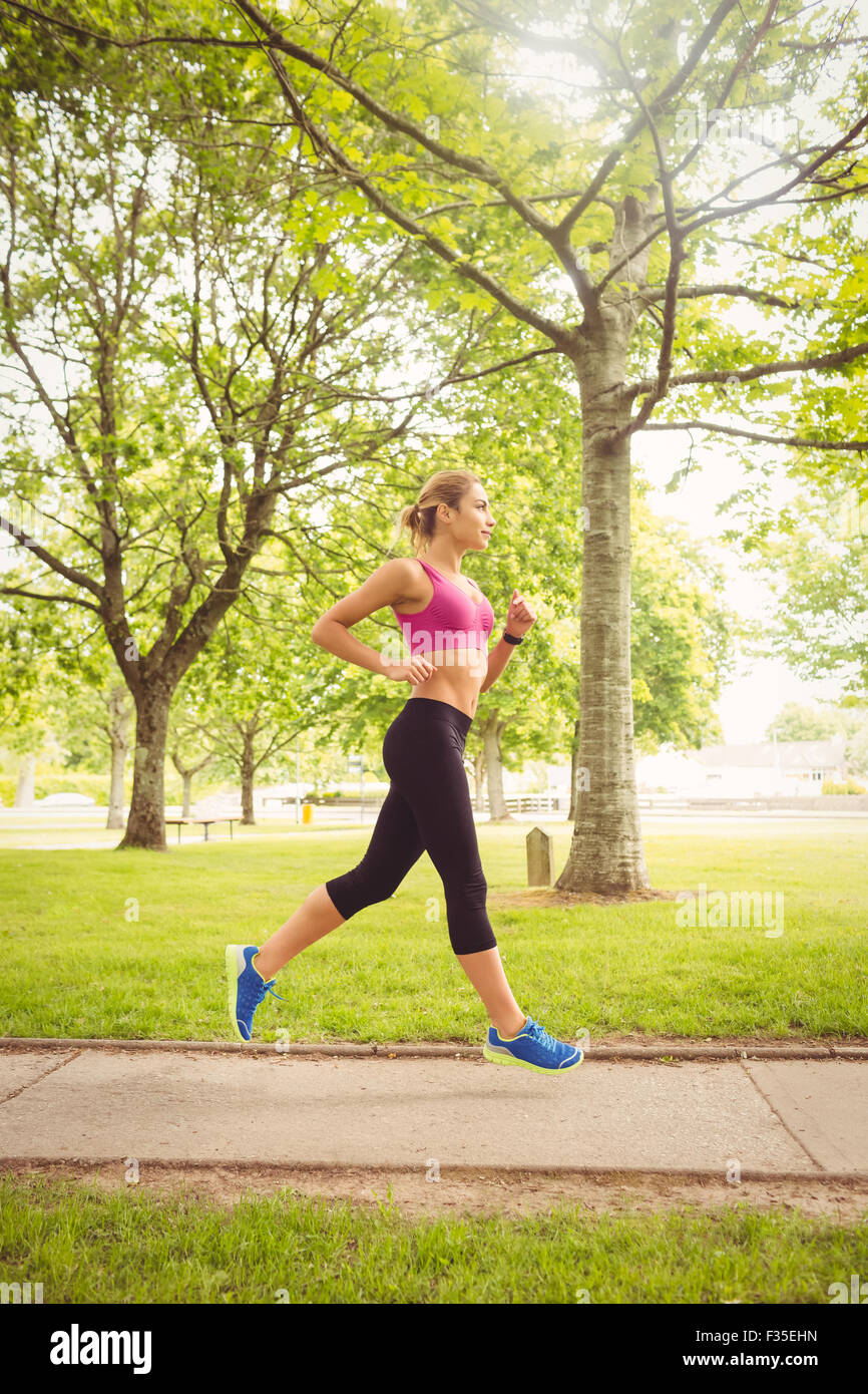 Side view of sporty woman jogging in park Stock Photo - Alamy
