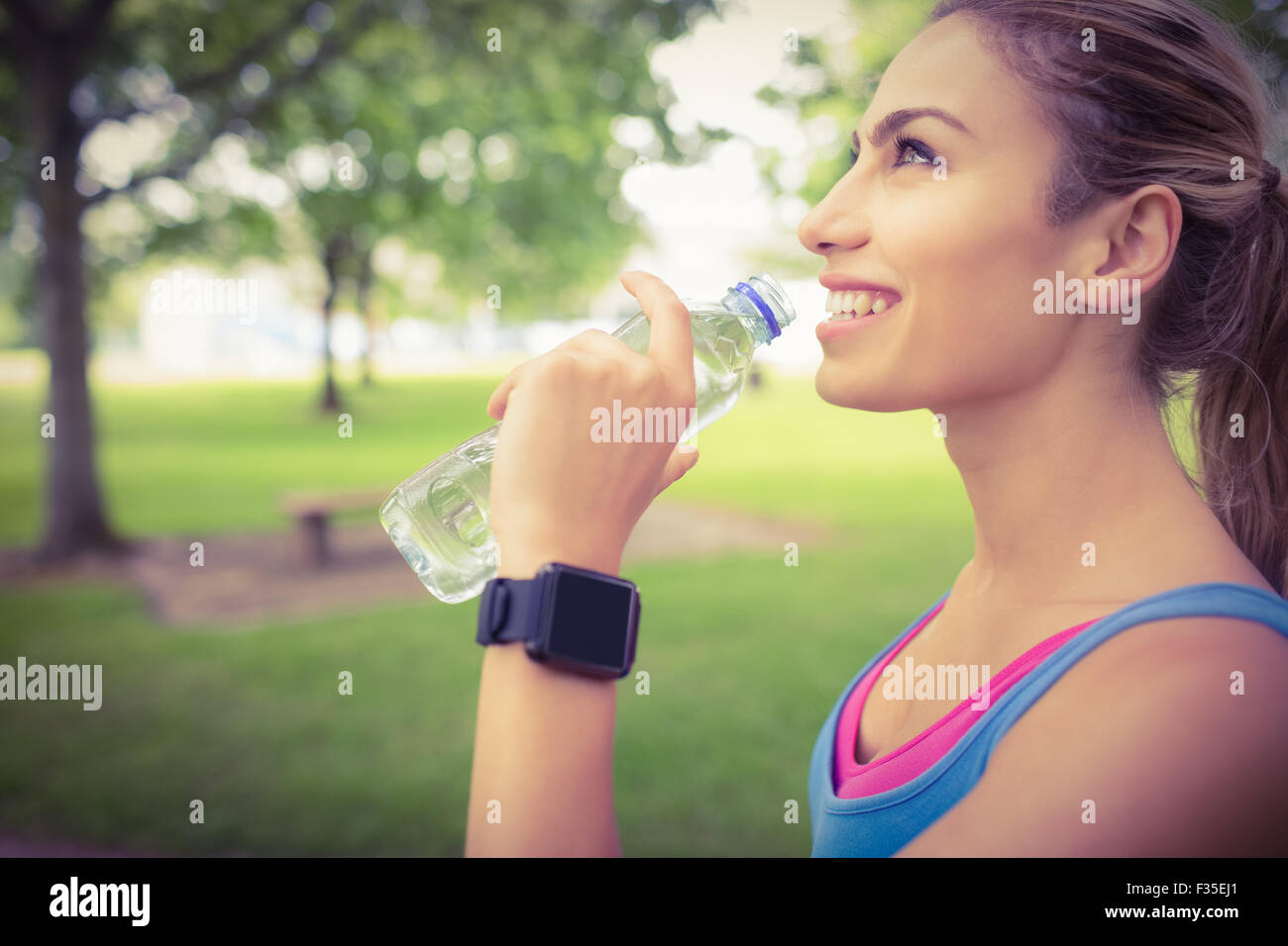 Smiling jogger woman drinking water in park Stock Photo - Alamy