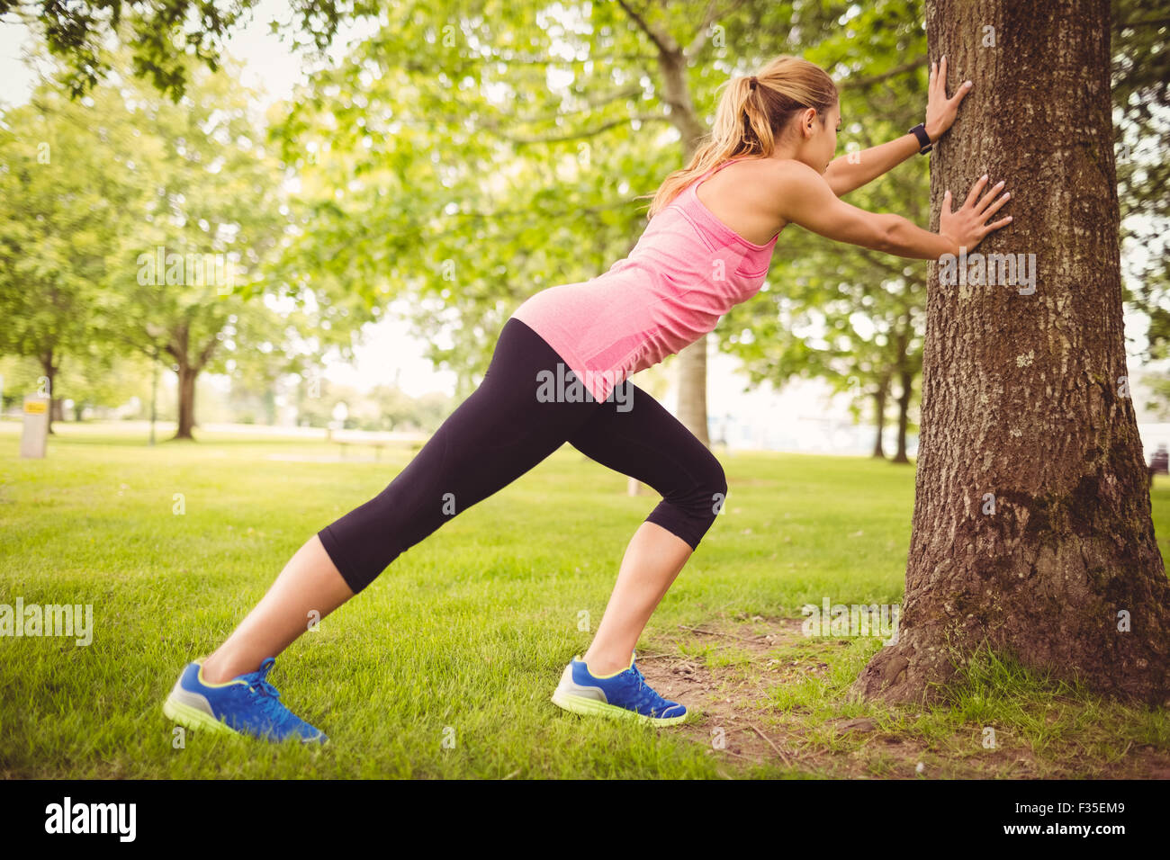 Full length of woman exercising with stretching body by tree Stock ...