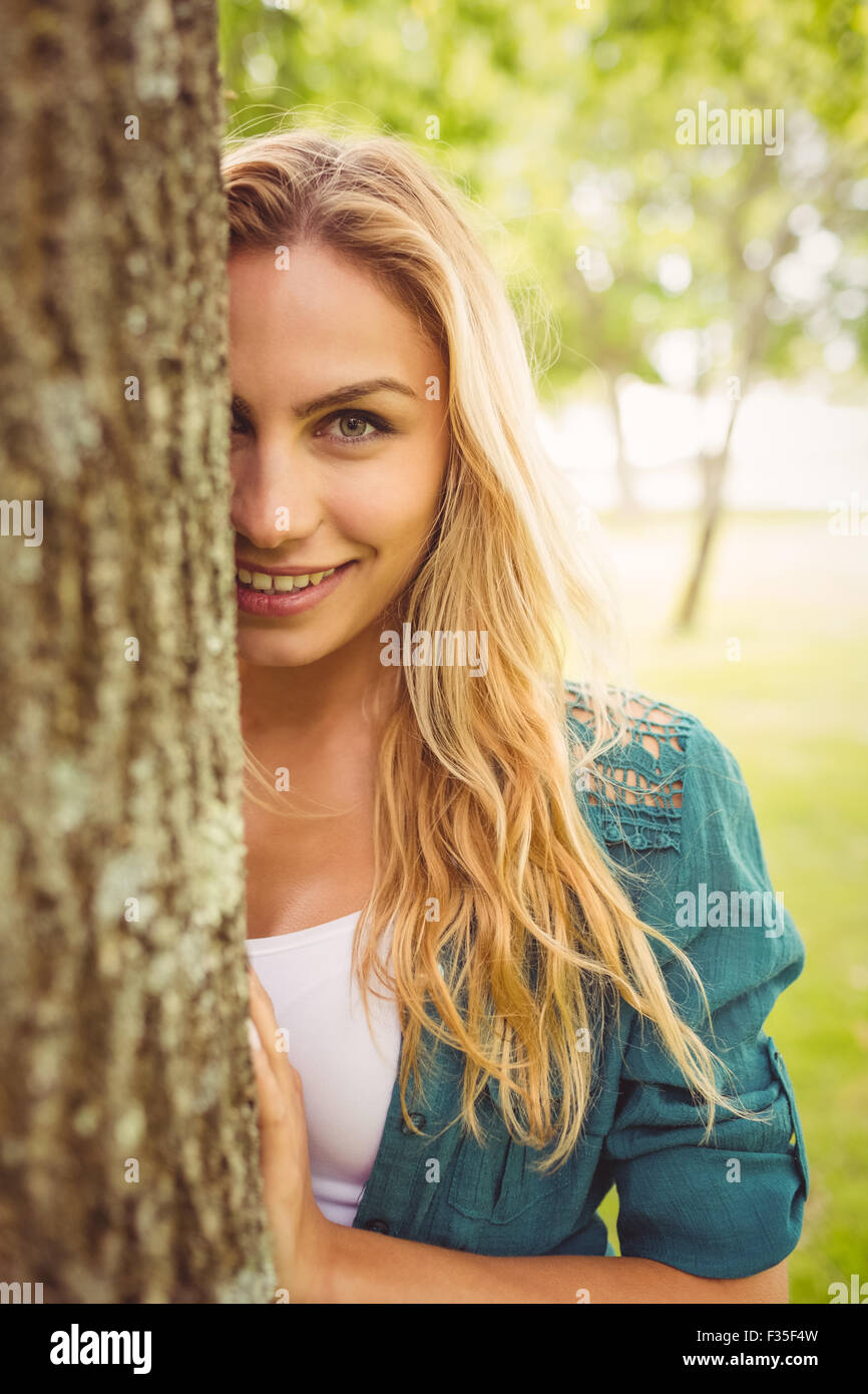 Portrait of beautiful smiling woman standing behind tree Stock Photo ...