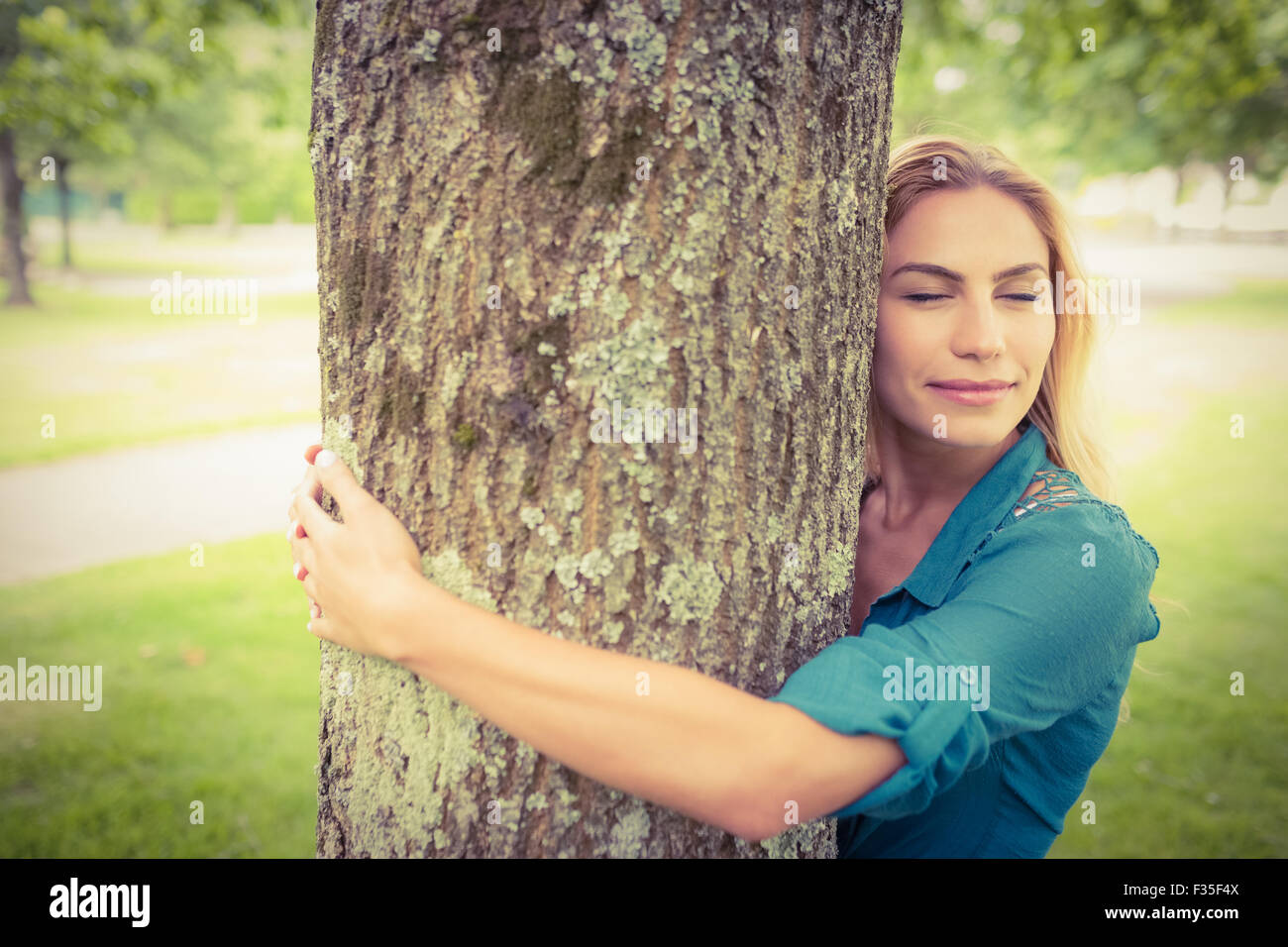 Smiling woman with eyes closed while hugging tree Stock Photo - Alamy