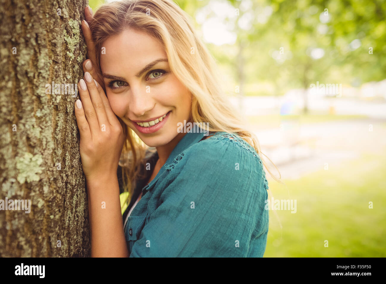 Portrait of beautiful smiling woman touching tree Stock Photo - Alamy