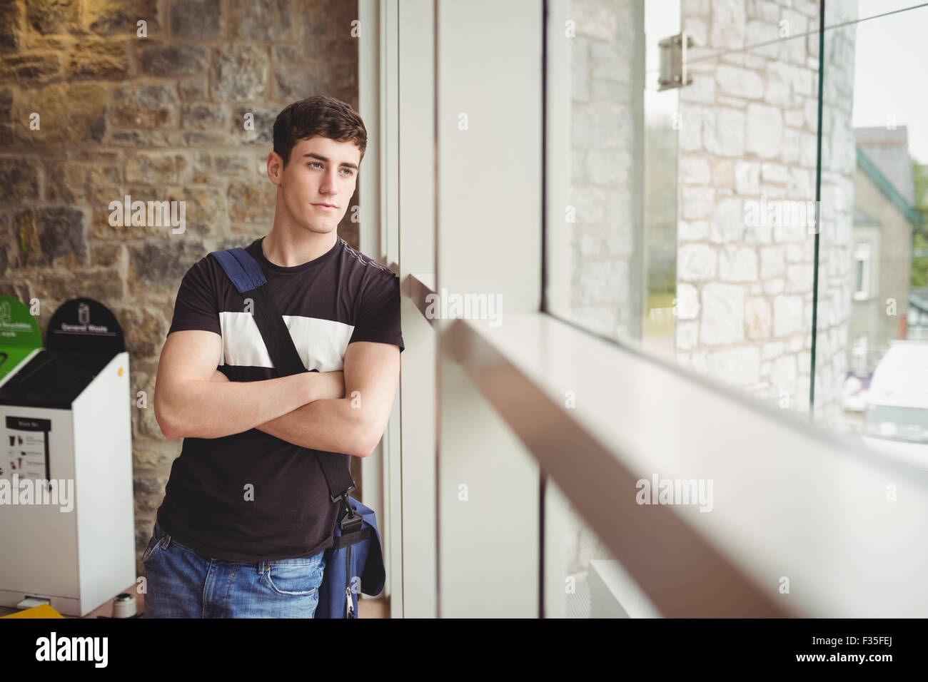 Thoughtful male student leaning on window Stock Photo - Alamy
