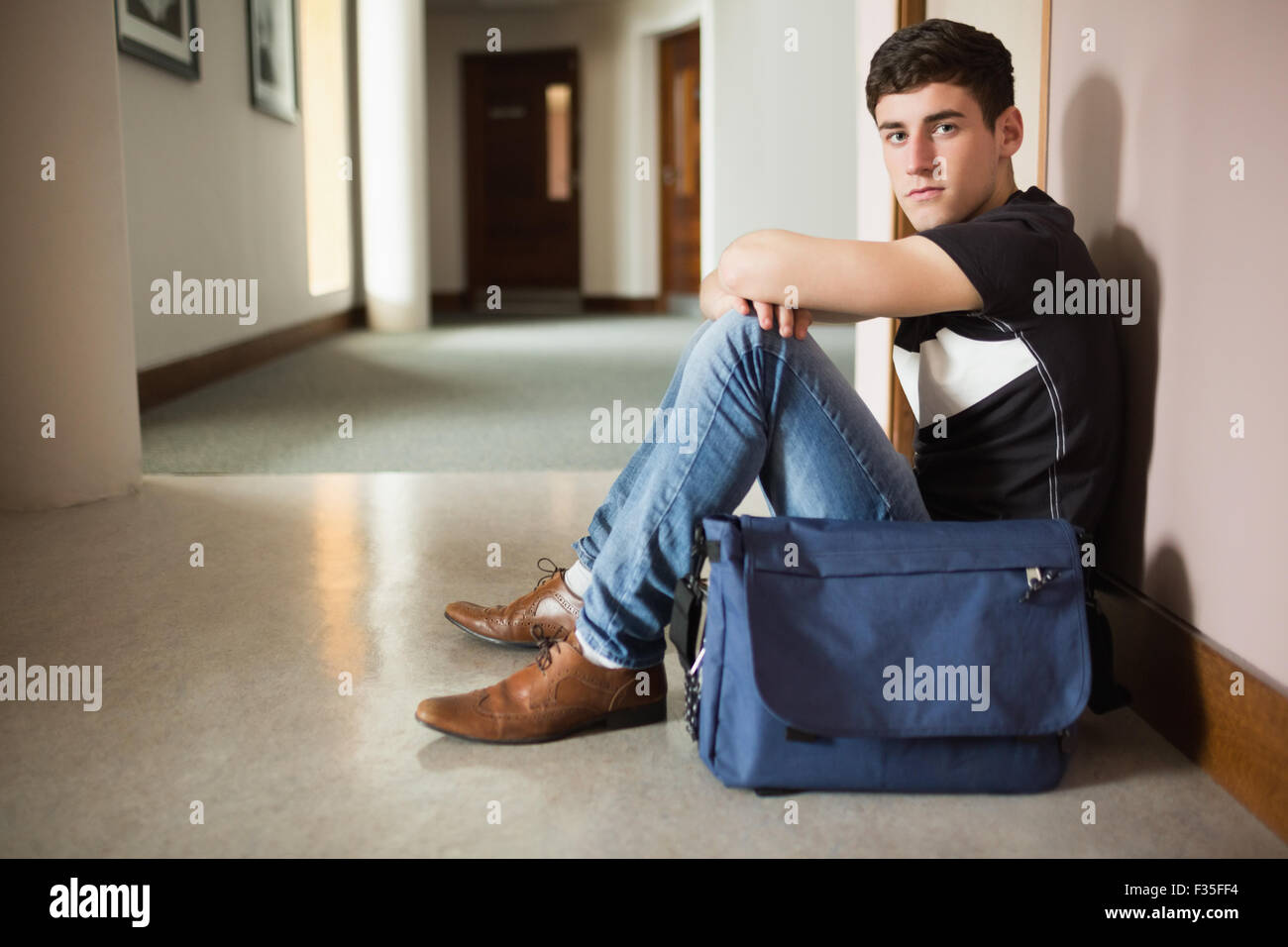 Portrait of male student sitting by wall Stock Photo - Alamy