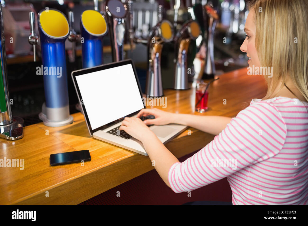 Woman working on laptop at bar counter Stock Photo - Alamy