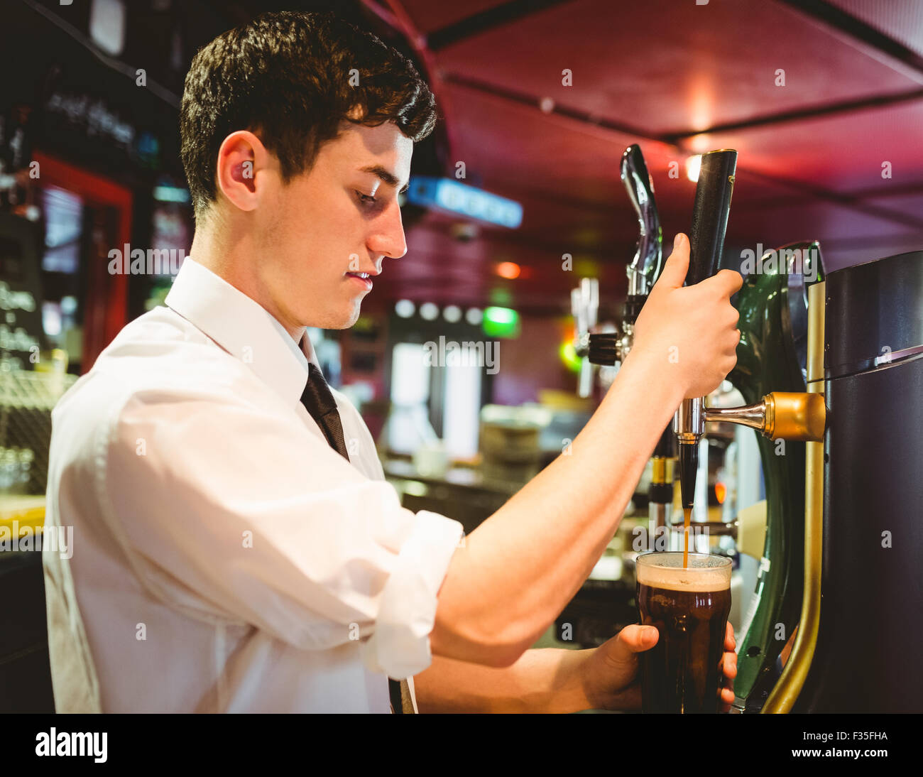Barkeeper holding beer glass below dispenser tap Stock Photo - Alamy