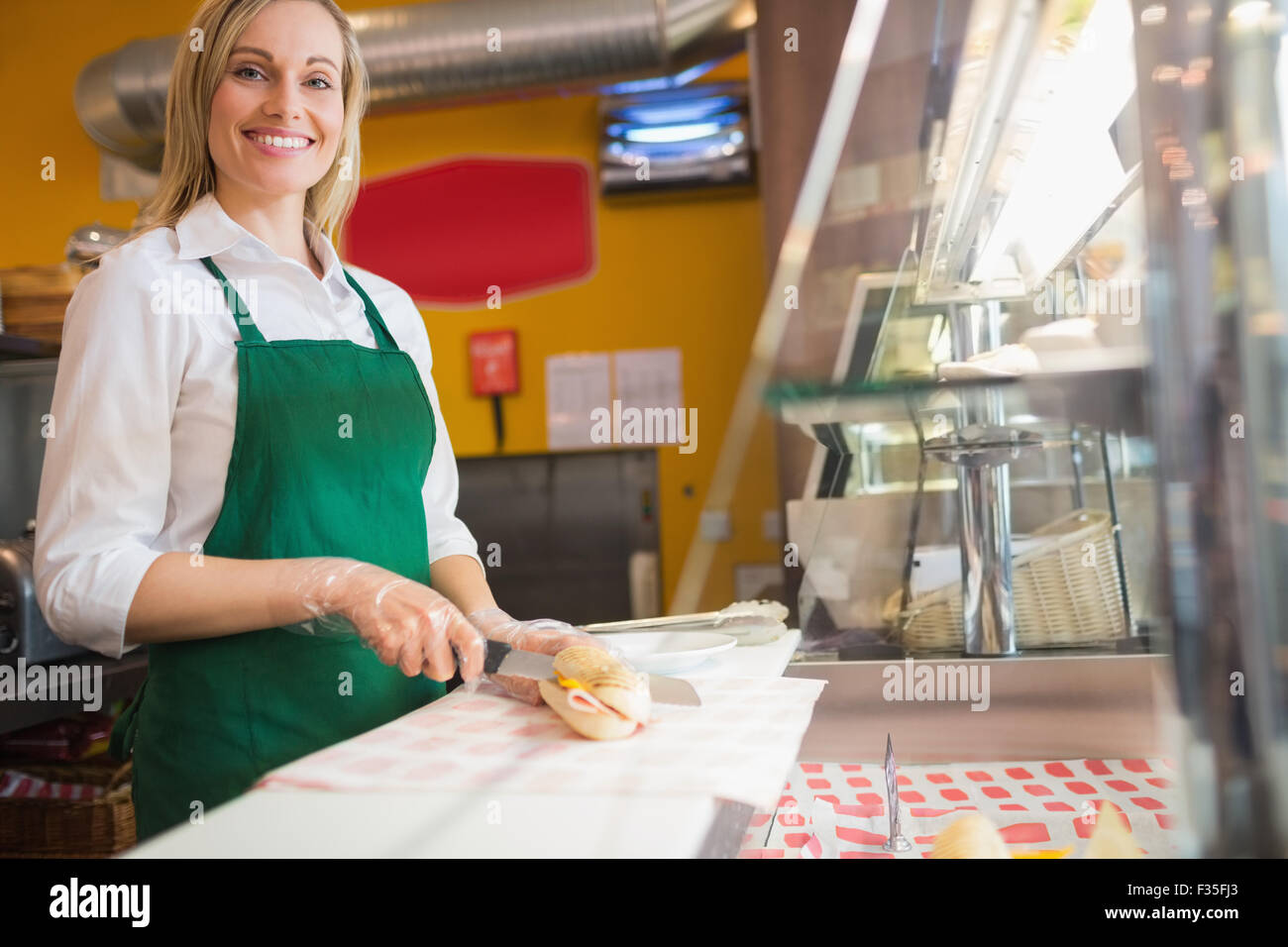 Female worker cutting sandwich on counter Stock Photo - Alamy