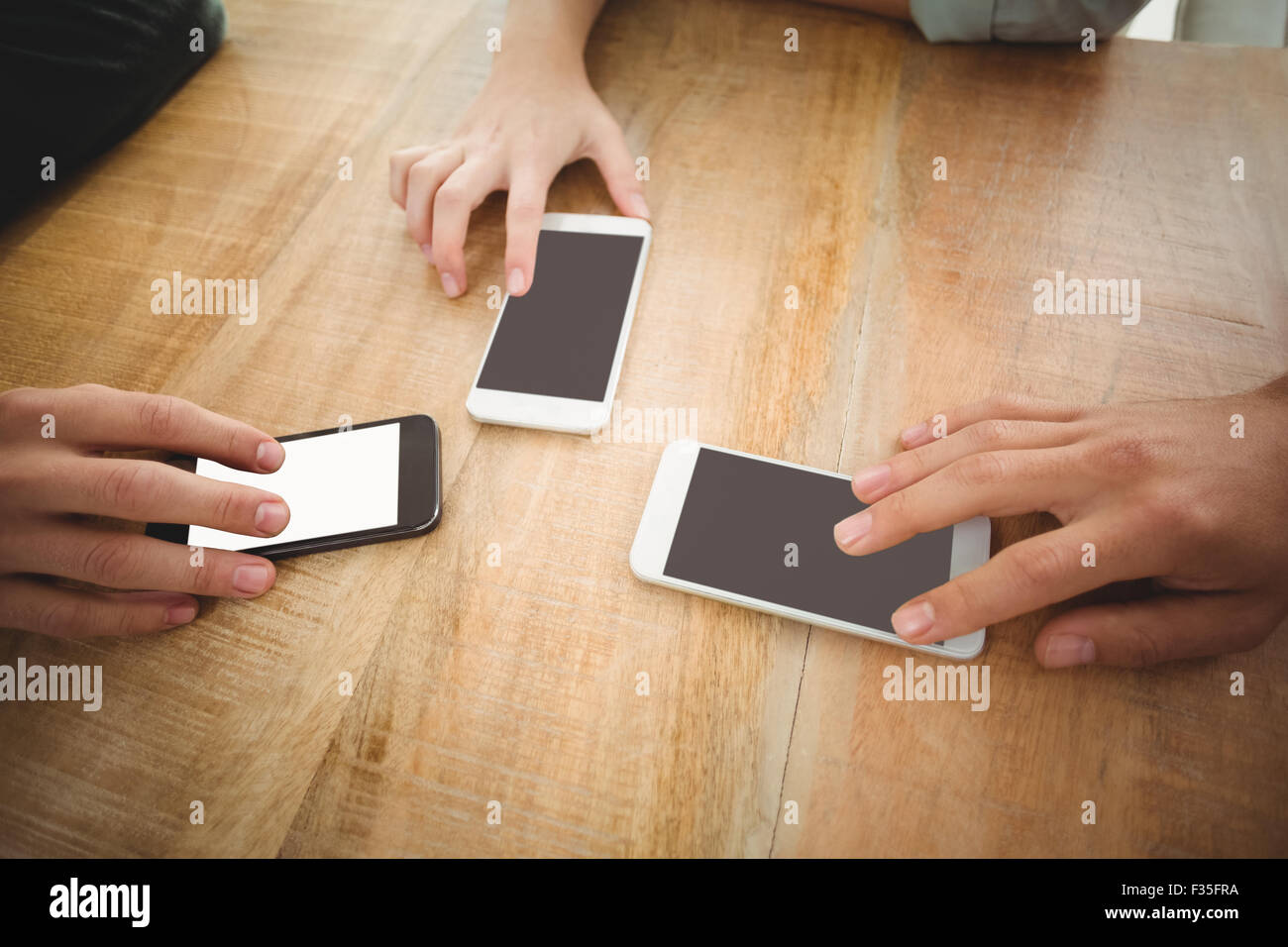Cropped hands touching smartphones at office Stock Photo - Alamy
