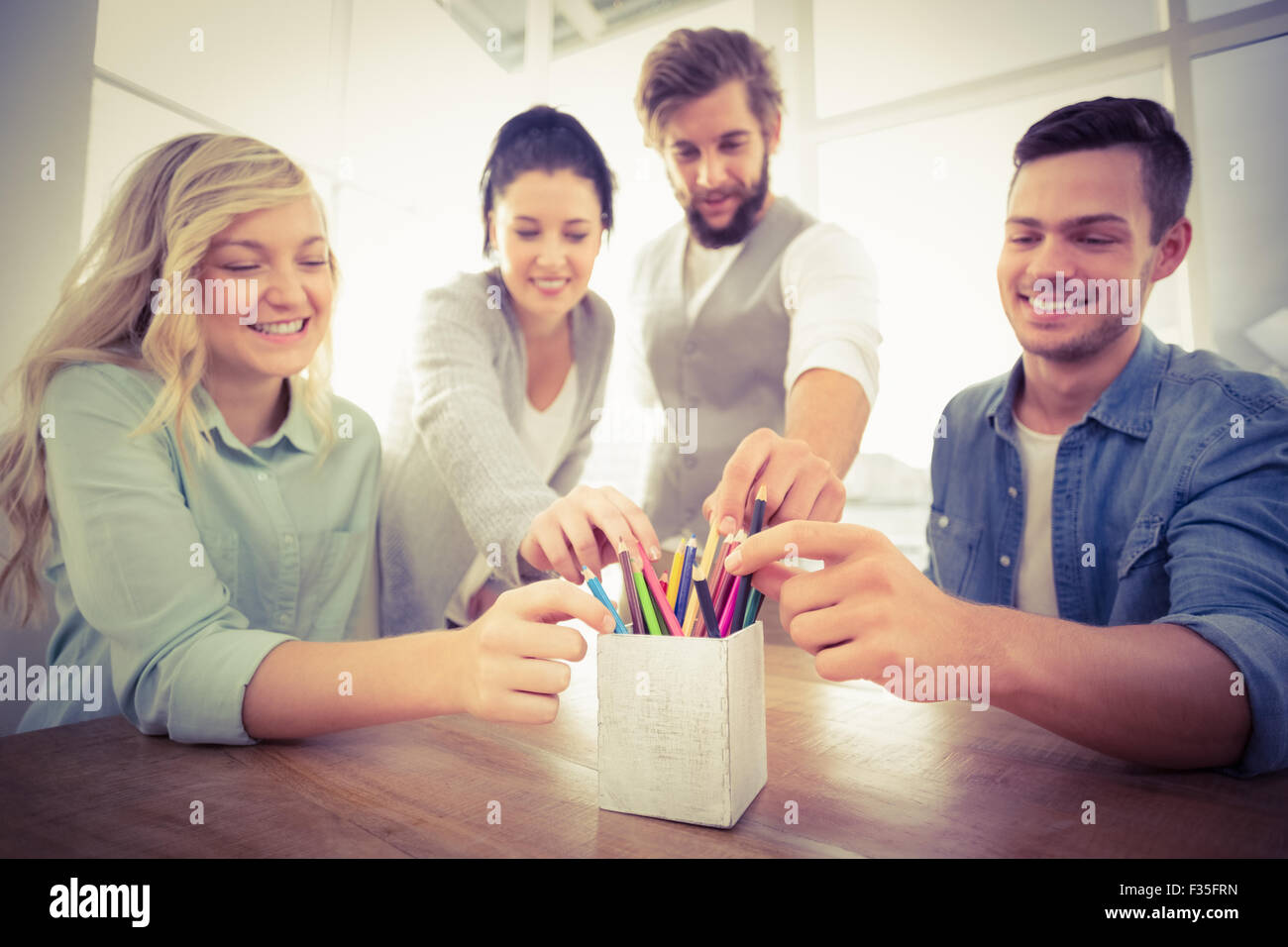 Smiling business people taking pencils Stock Photo - Alamy