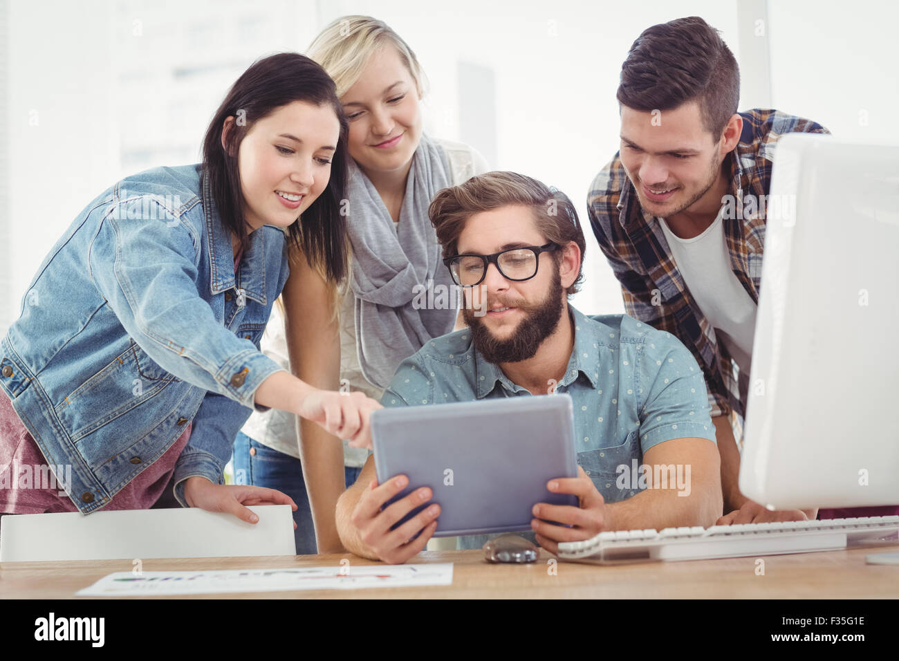 Business people using digital tablet while sitting at computer desk ...