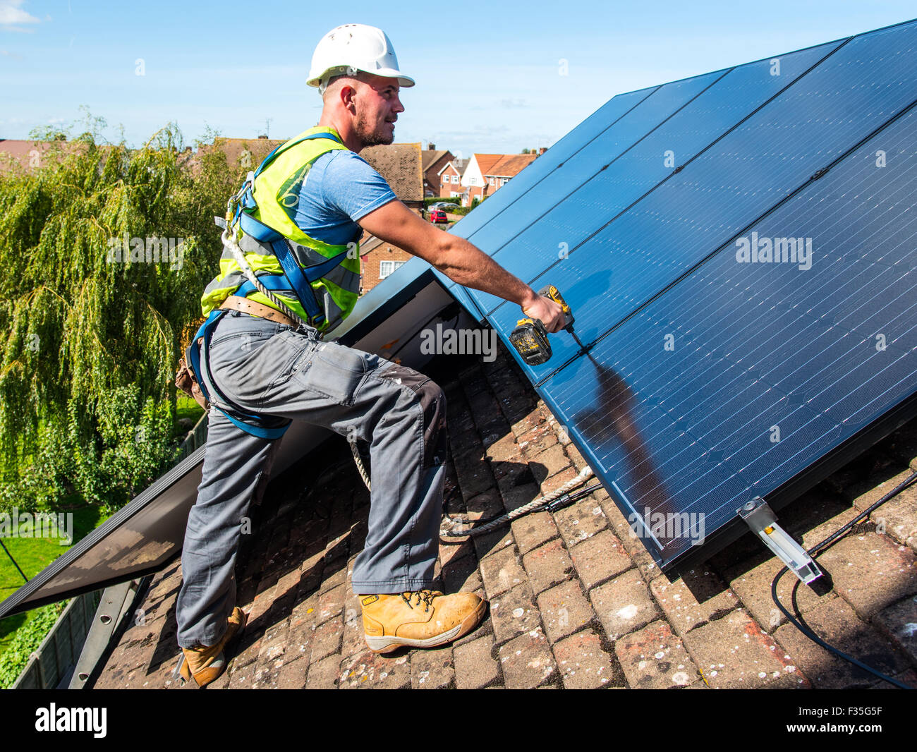 Roofer fitting a domestic solar panel system Stock Photo - Alamy