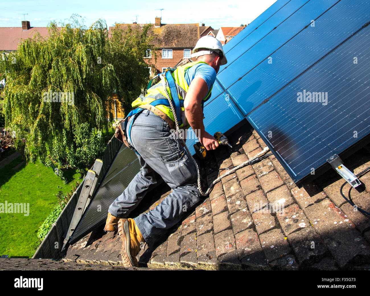 Roofer fitting a domestic solar panel system Stock Photo - Alamy