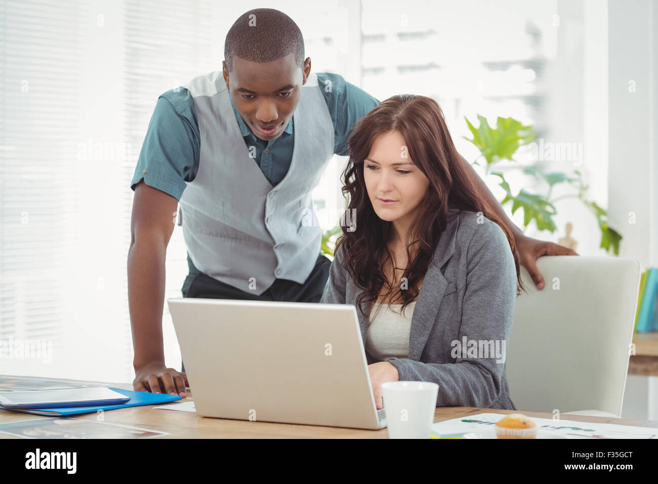 Businesswoman working on laptop with coworker Stock Photo - Alamy