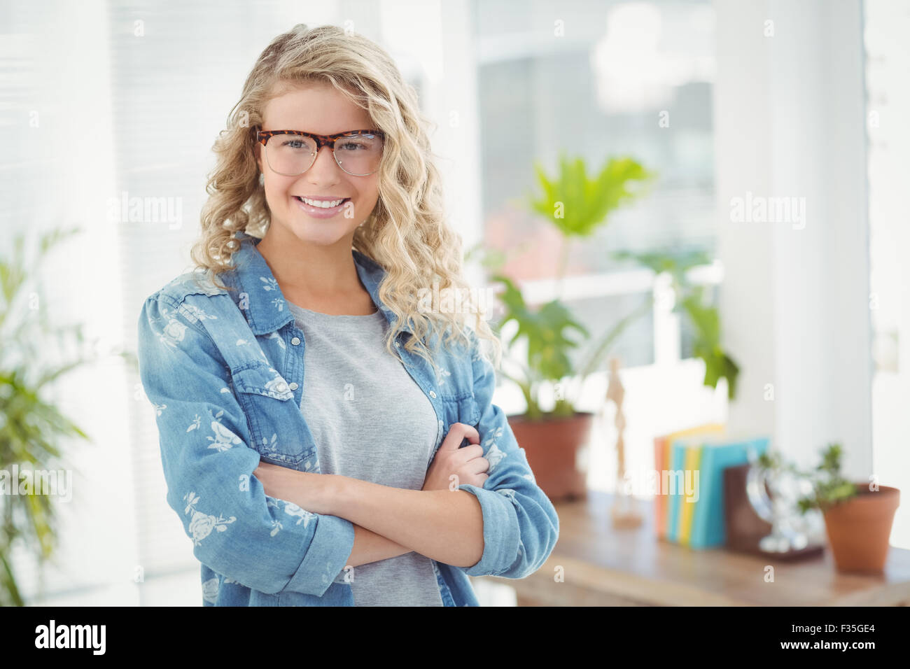 Portrait of smiling businesswoman wearing eyeglasses with arms crossed ...