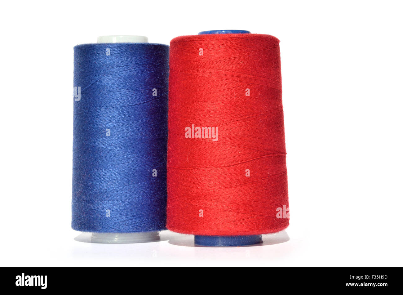 Reels of blue and red thread on white background Stock Photo - Alamy