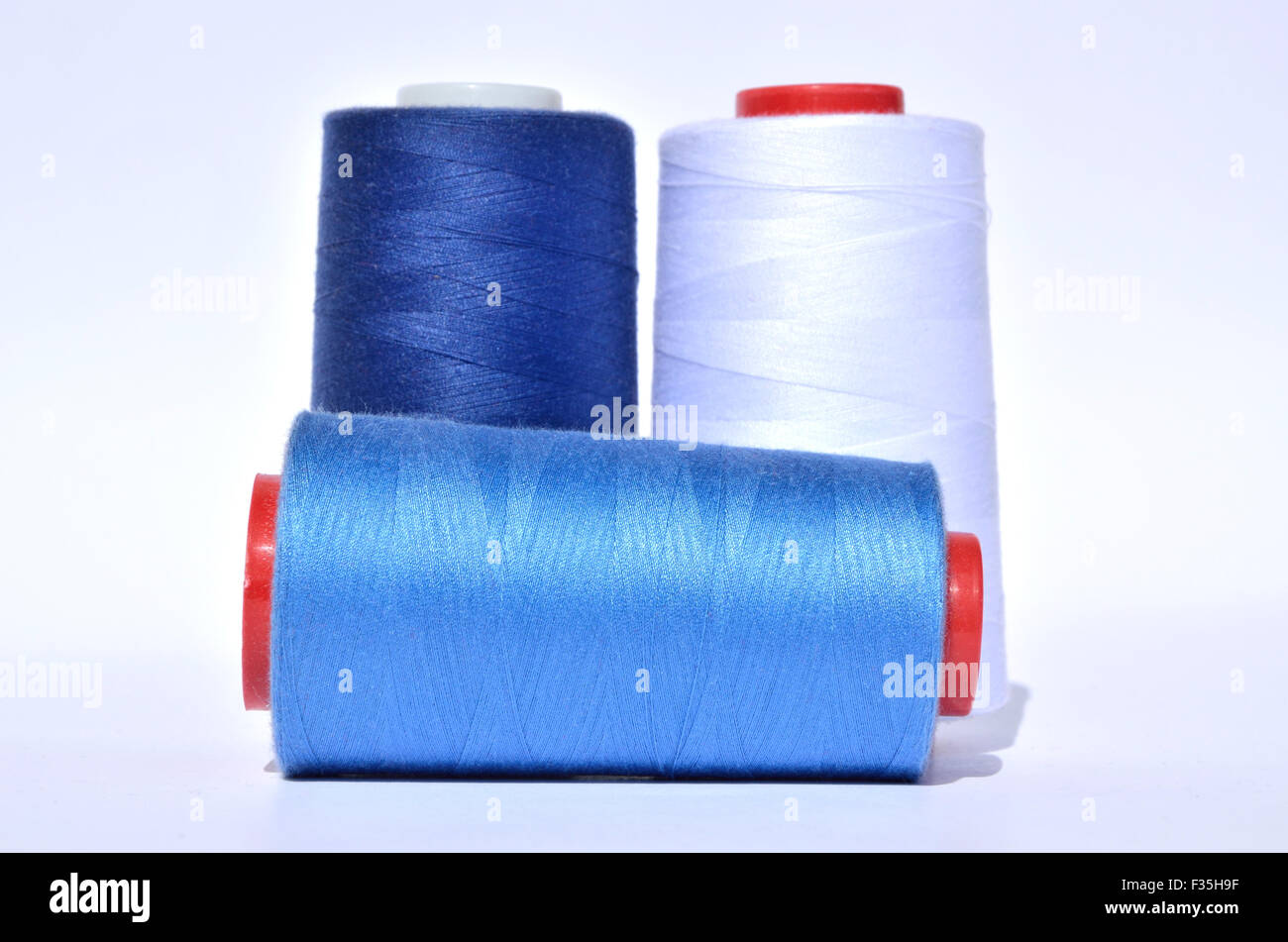 Reels of blue and white threads on white background Stock Photo - Alamy