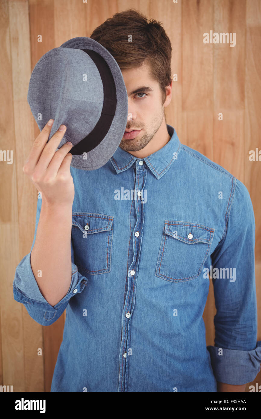 Portrait of hipster holding hat in front of face Stock Photo - Alamy