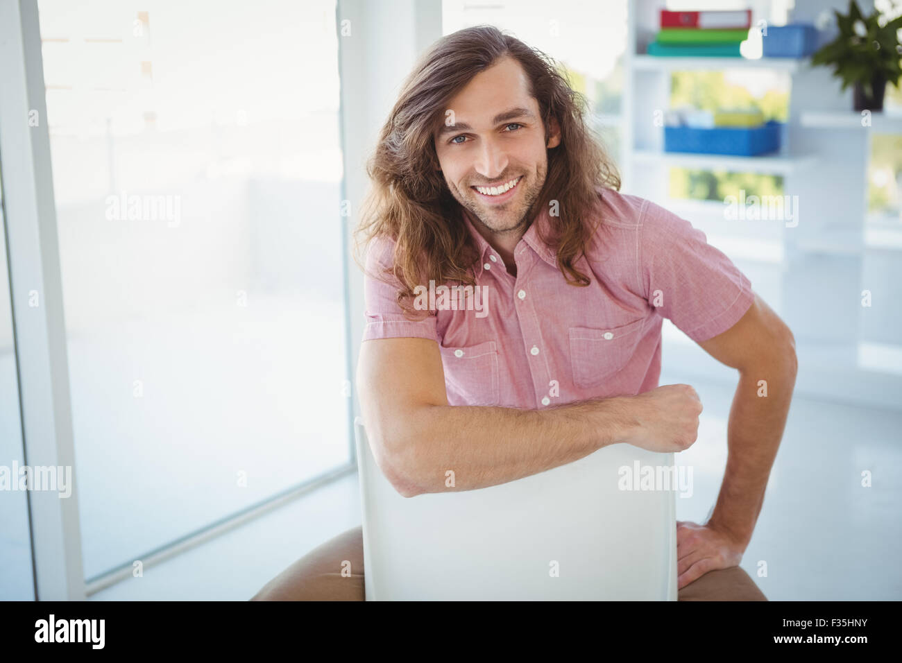 Portrait of hipster smiling while sitting on chair Stock Photo - Alamy