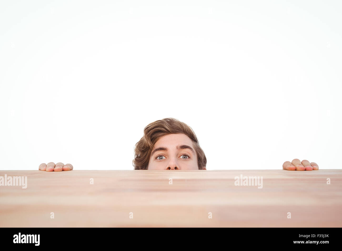 Man hiding behind desk against white background Stock Photo - Alamy