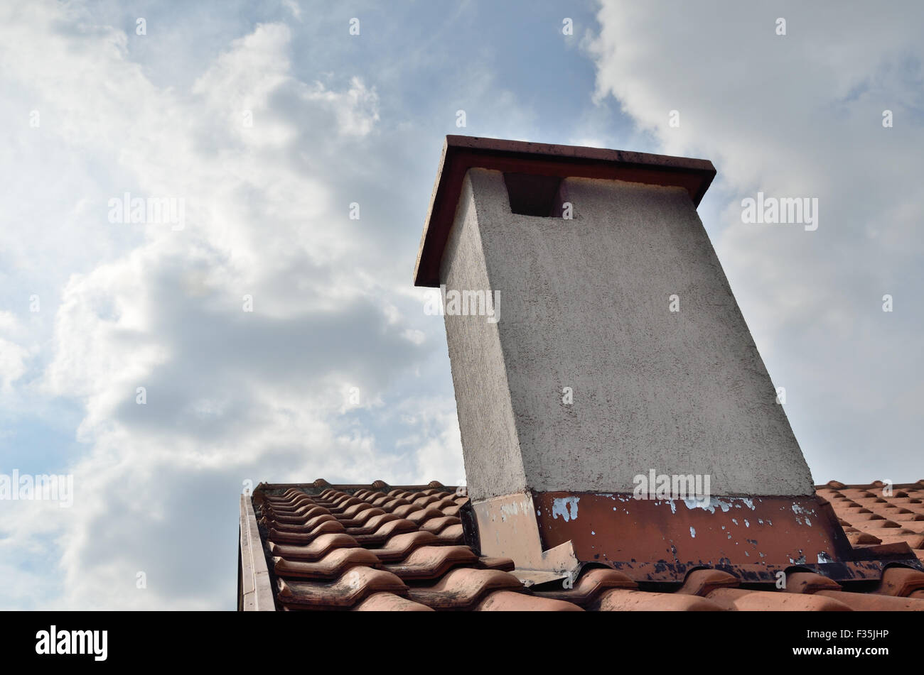 Chimney on tiled roof and cloudy sky Stock Photo - Alamy
