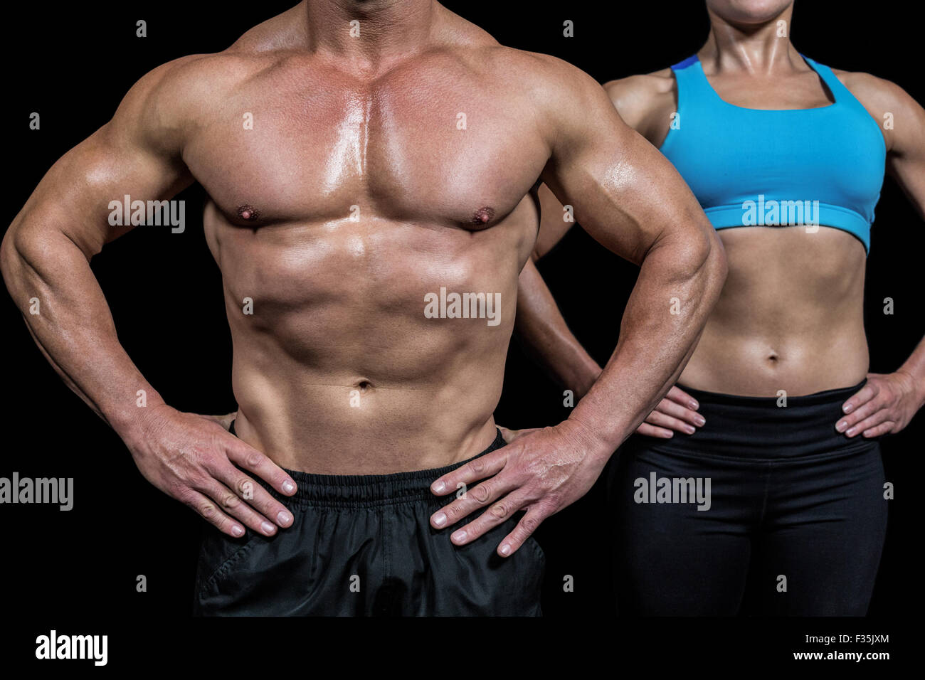 Midsection of muscular man and woman standing with hands on hip Stock ...