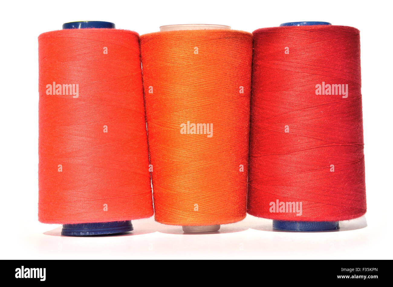 Reels of red and orange thread on white background Stock Photo - Alamy