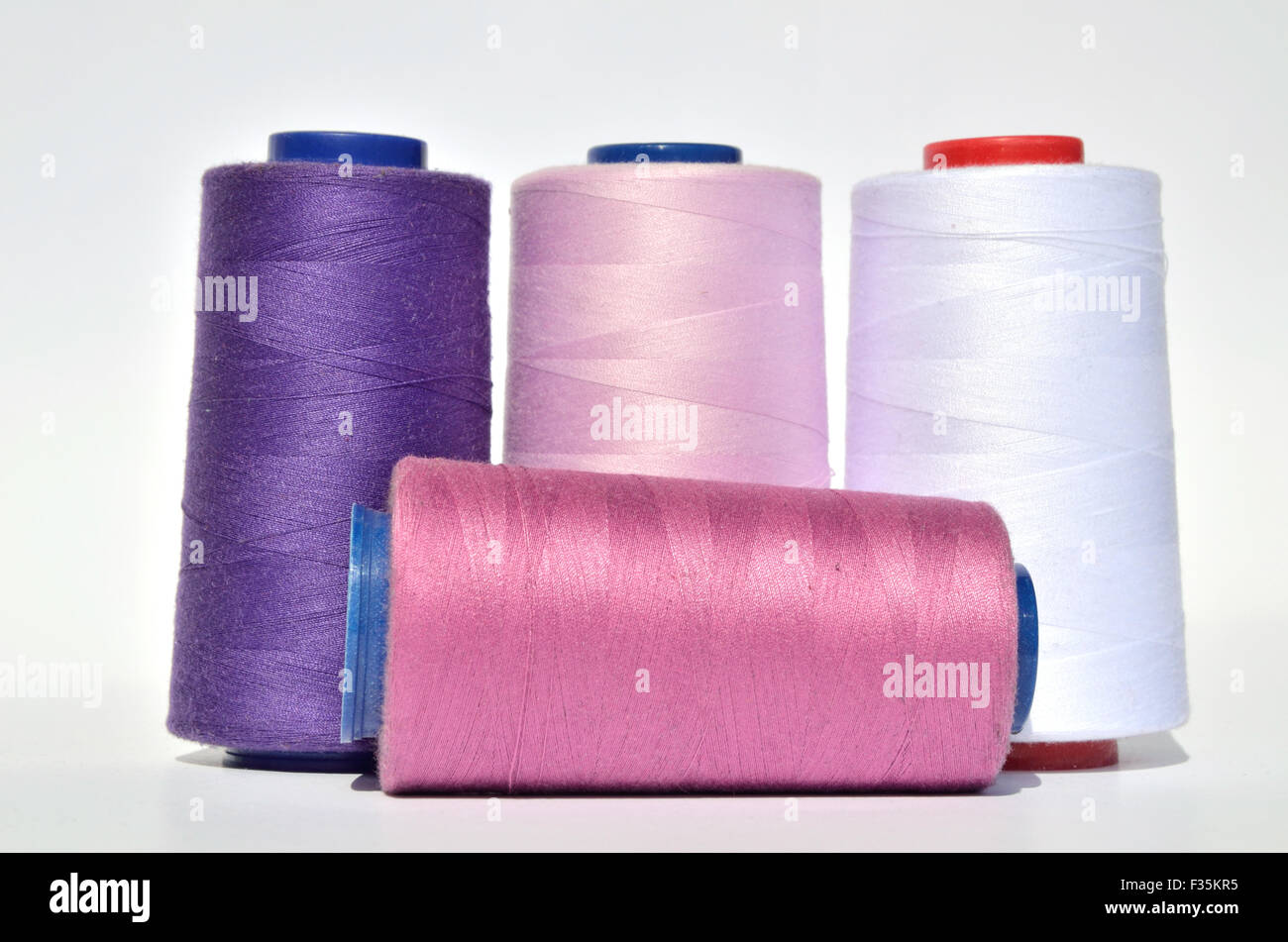 Reels of pink, violet and white thread on white background Stock Photo ...