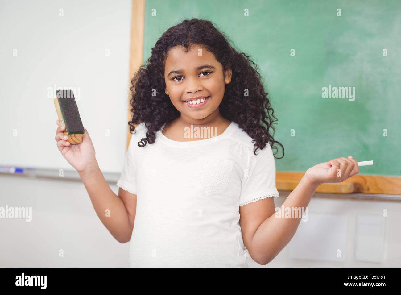 Smiling pupil holding chalk in a classroom Stock Photo - Alamy