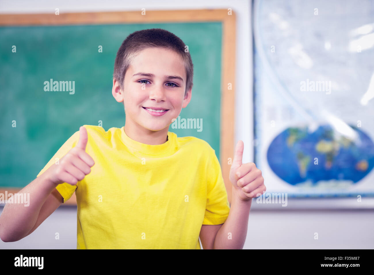 Smiling pupil doing thumbs up in a classroom Stock Photo - Alamy