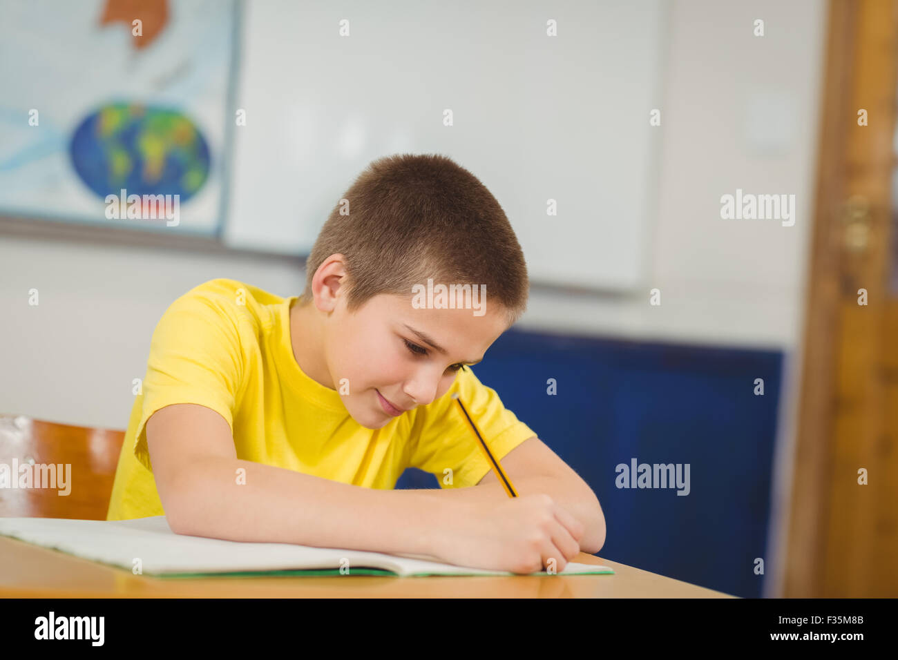 Smiling pupil working at his desk in a classroom Stock Photo - Alamy