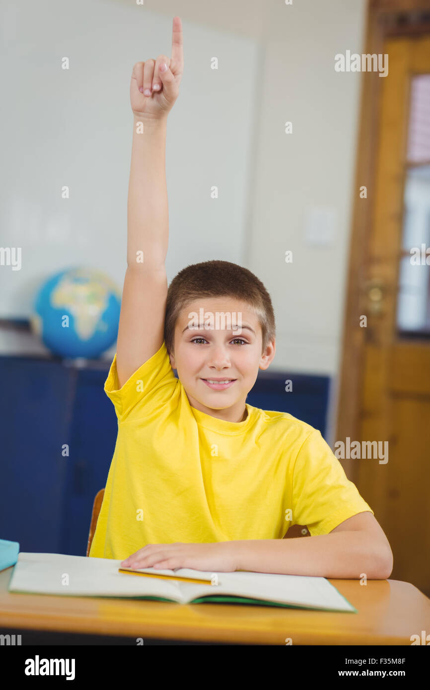 Smiling pupil raising hand in a classroom Stock Photo - Alamy