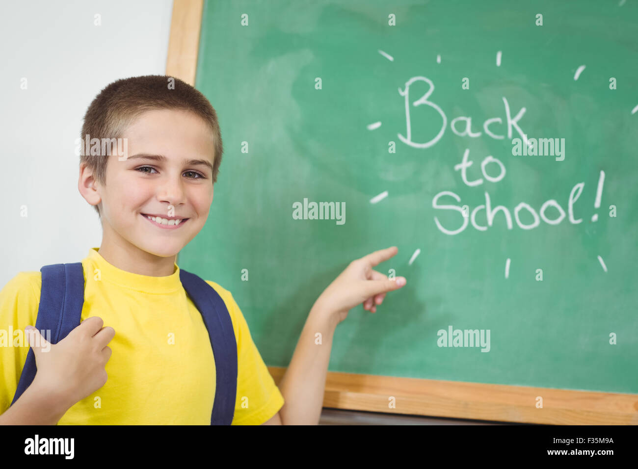 Smiling pupil pointing on back to school sign on chalkboard Stock Photo ...