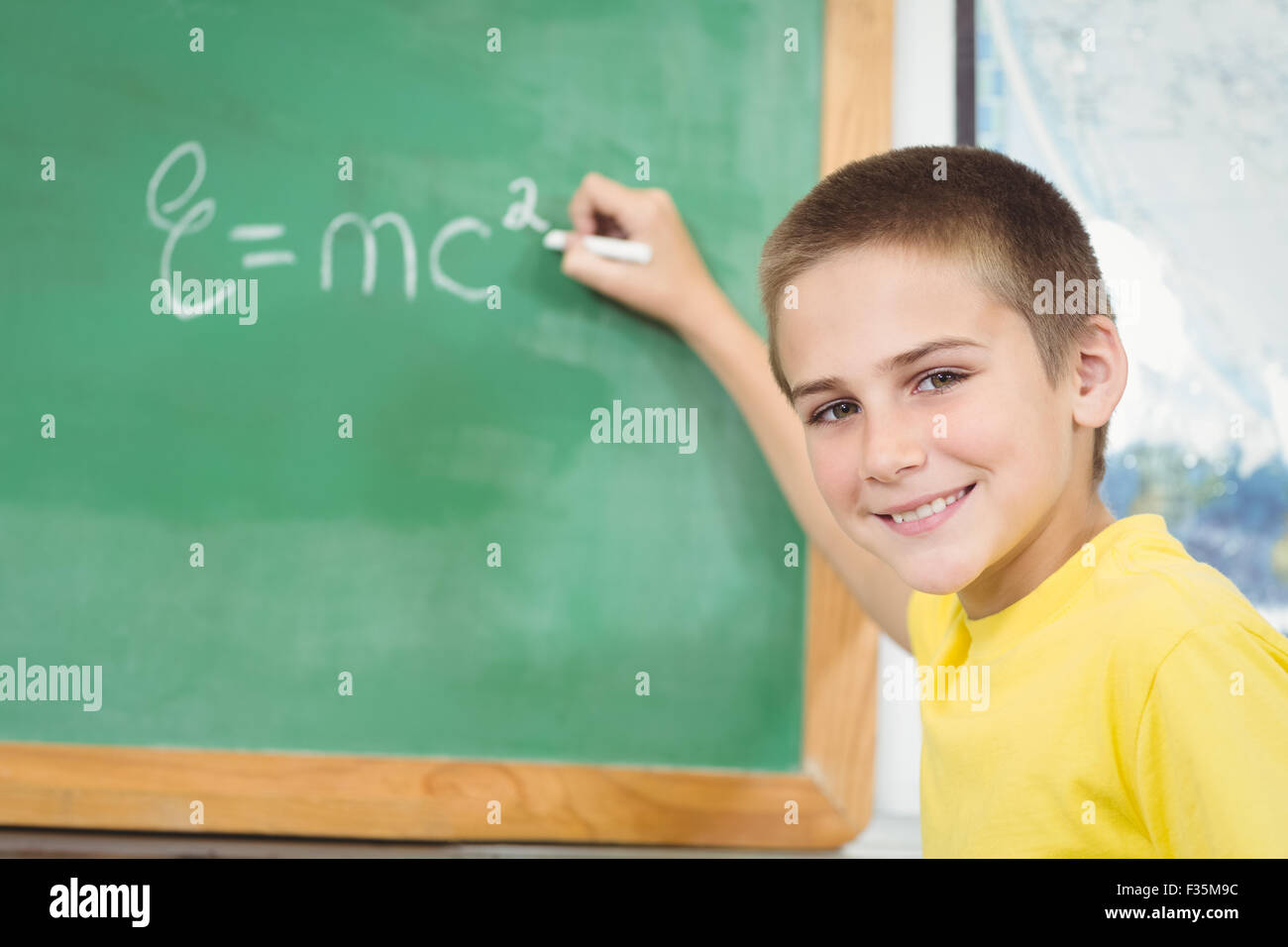 Smiling pupil writing on chalkboard in a classroom Stock Photo - Alamy