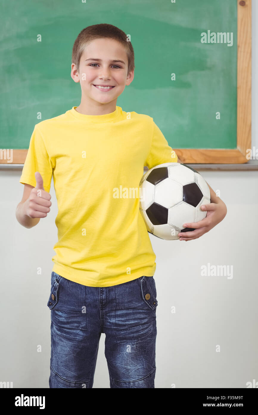 Smiling pupil holding football in a classroom Stock Photo - Alamy
