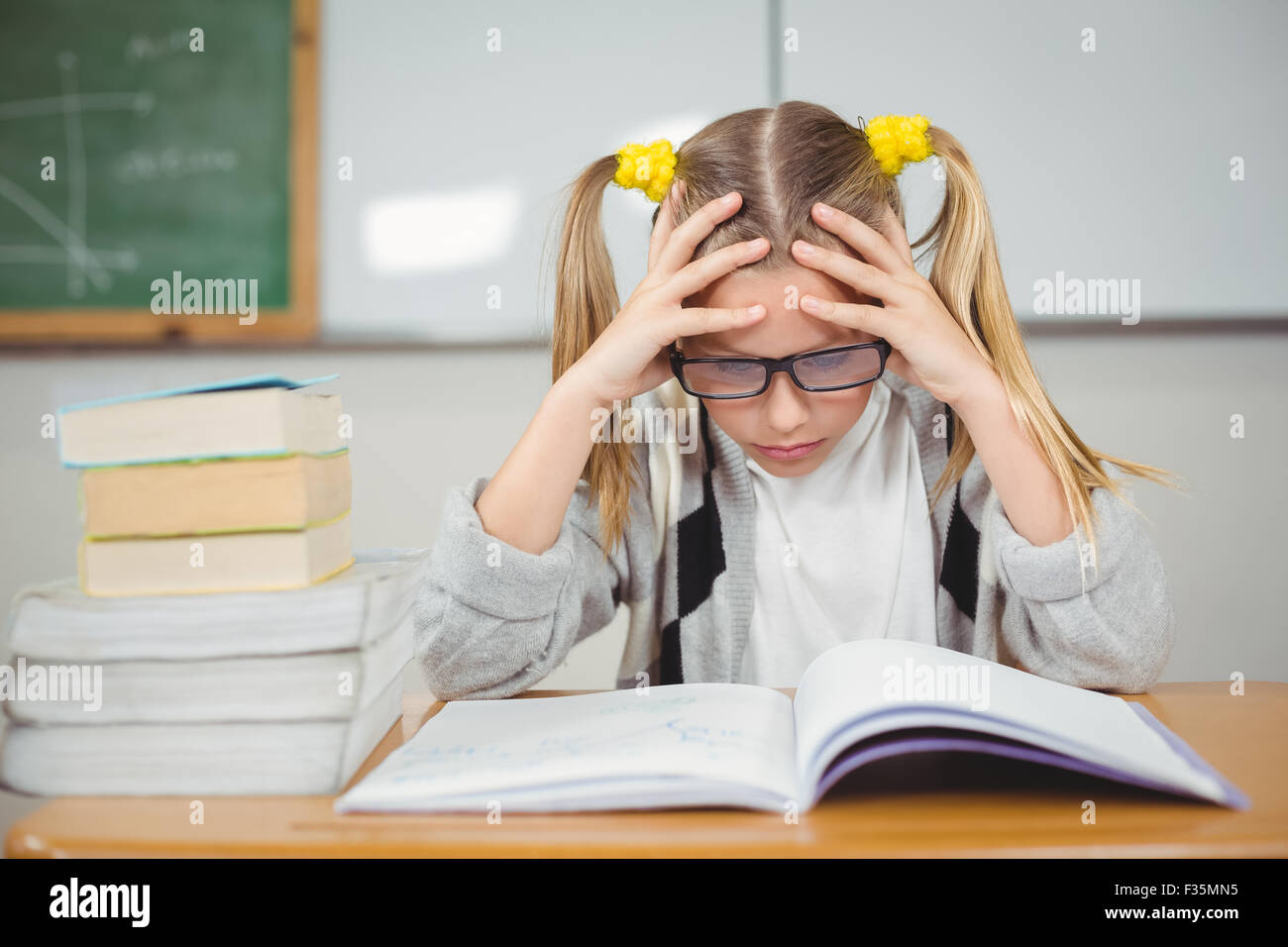 Concentrated pupil reading book at her desk Stock Photo - Alamy