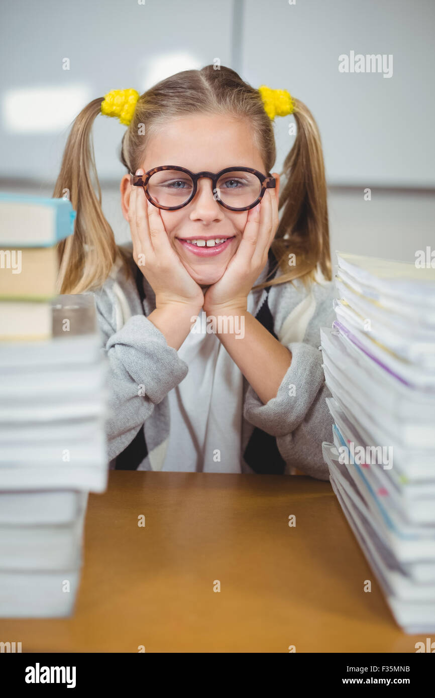 Smiling pupil between stack of books on her desk Stock Photo - Alamy