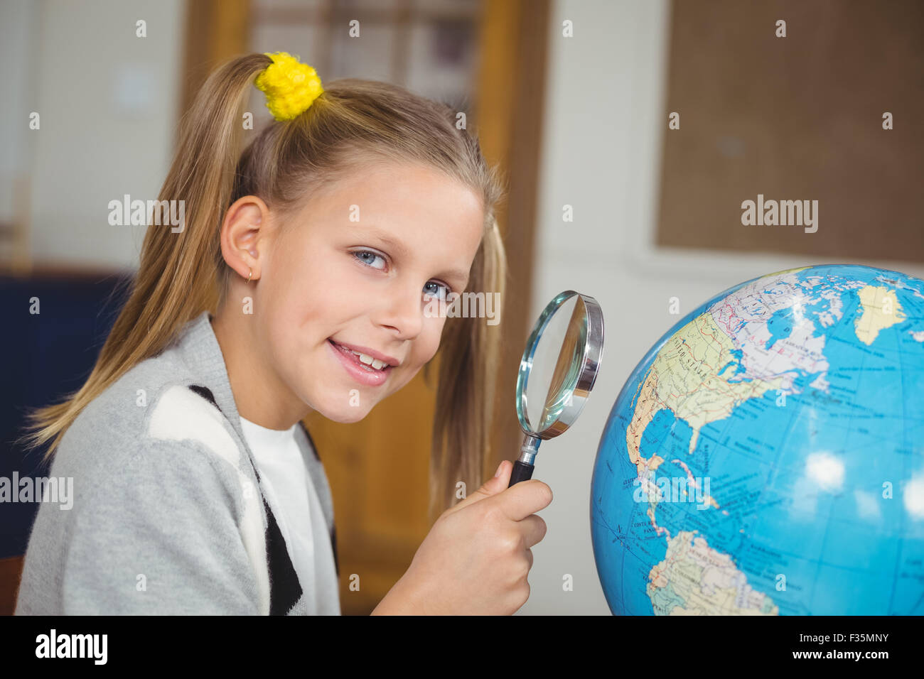 Cute pupil looking at globe through magnifier Stock Photo - Alamy