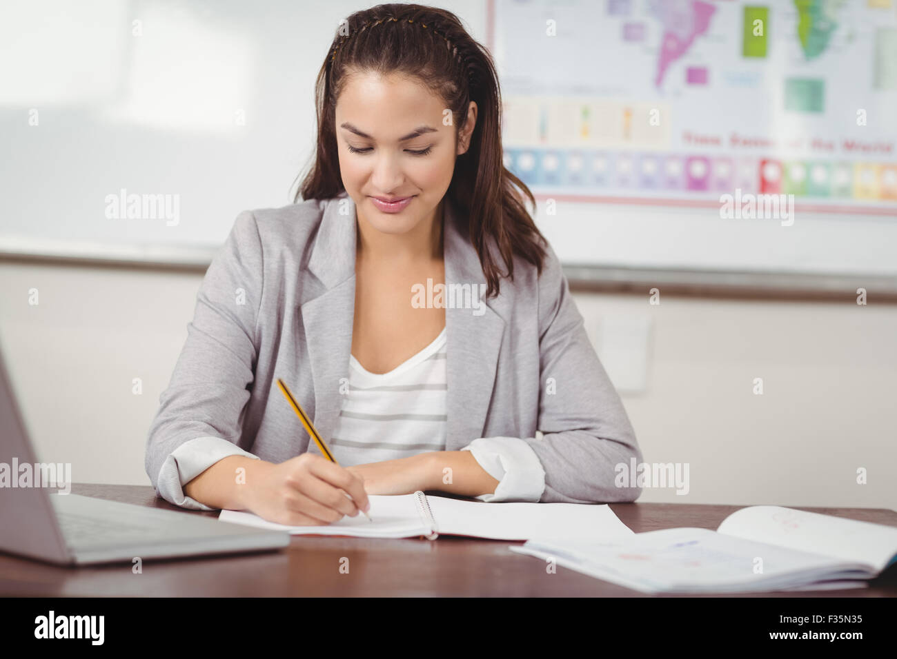 Pretty teacher correcting at her desk in a classroom Stock Photo - Alamy