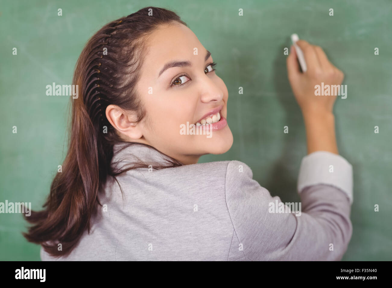 Rear view of pretty teacher writing on chalkboard Stock Photo - Alamy