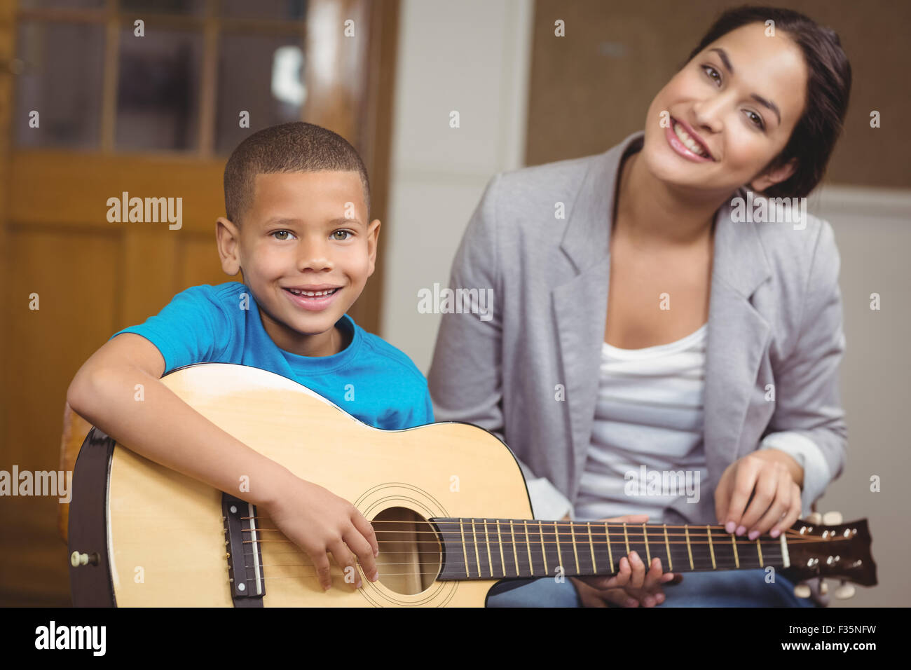 Pretty teacher giving guitar lessons to pupil Stock Photo - Alamy