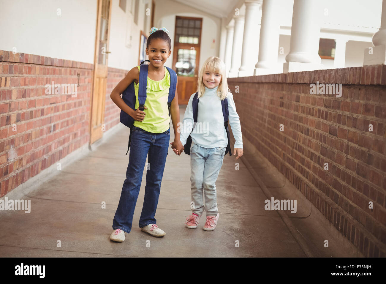 Smiling pupils holding hands at corridor Stock Photo - Alamy