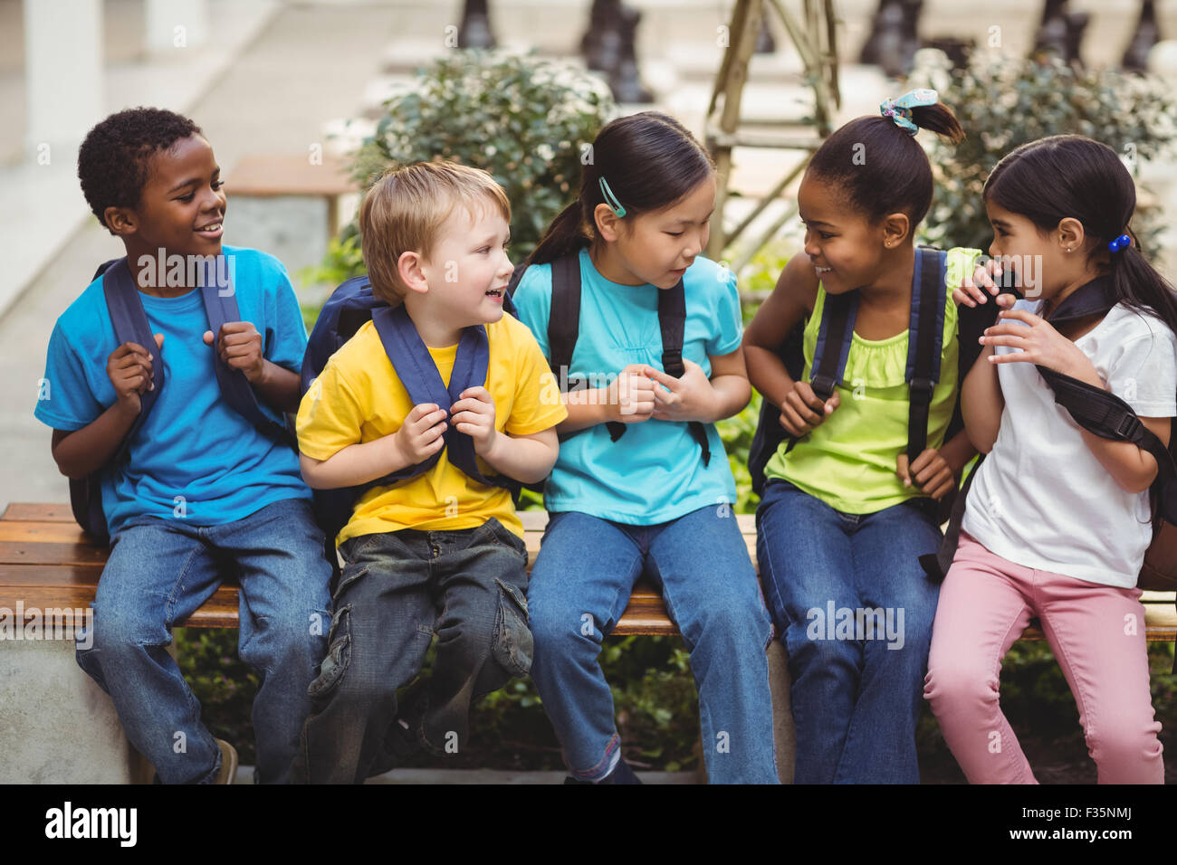 Happy pupils with schoolbags sitting on bench Stock Photo - Alamy