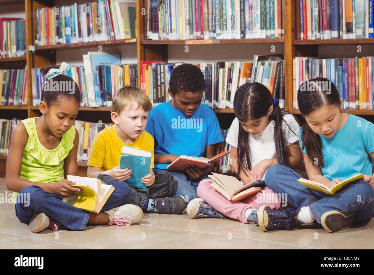 Pupils sitting on the ground and reading books in the library Stock ...