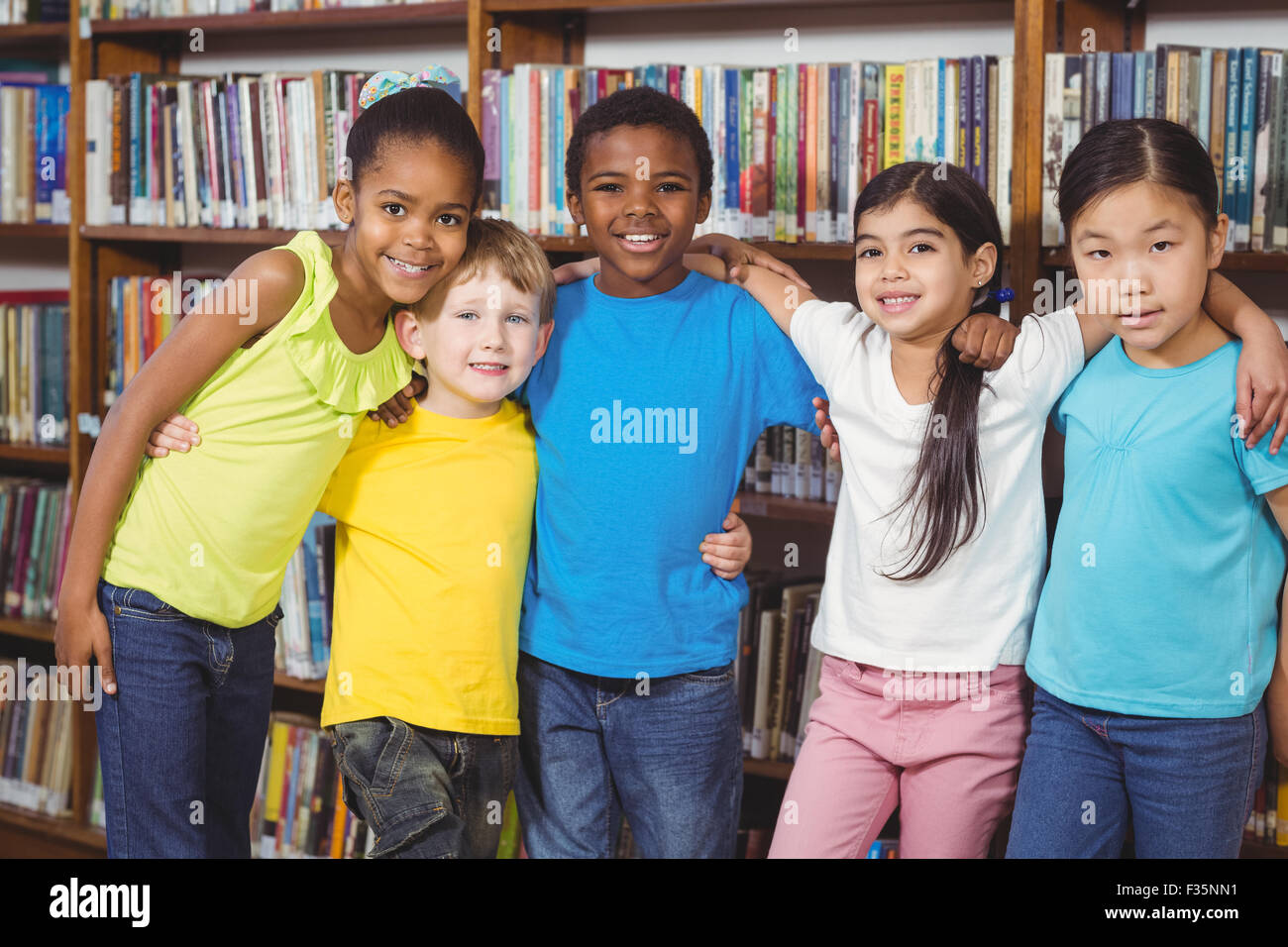 Happy pupils having arms around in the library Stock Photo - Alamy