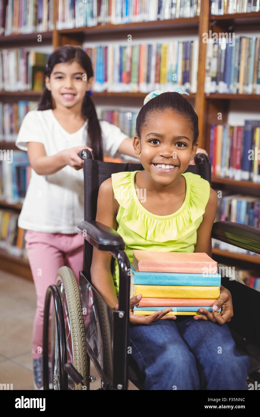 Smiling pupil in wheelchair holding books in the library Stock Photo ...