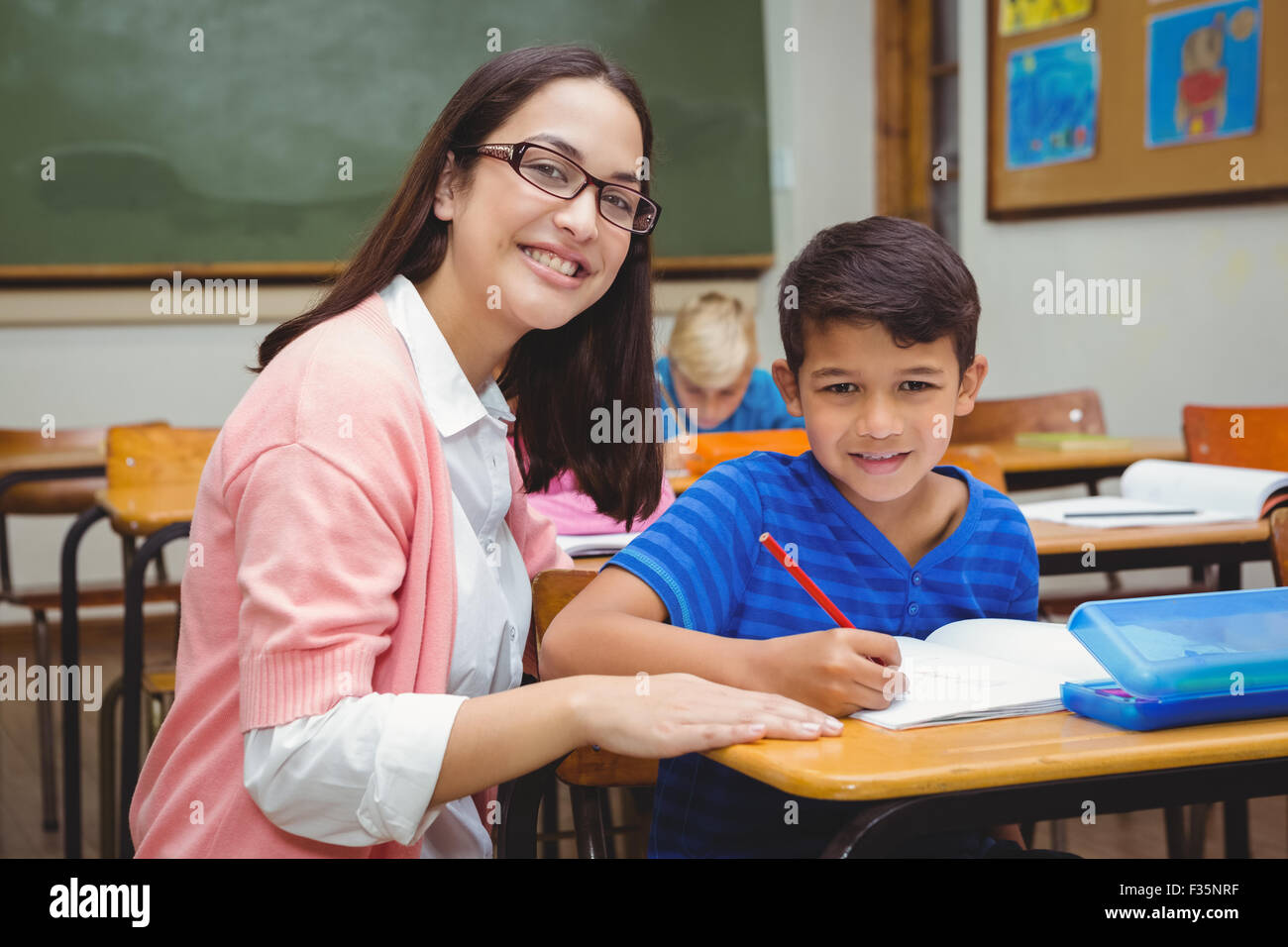 Happy teacher helping her students Stock Photo - Alamy