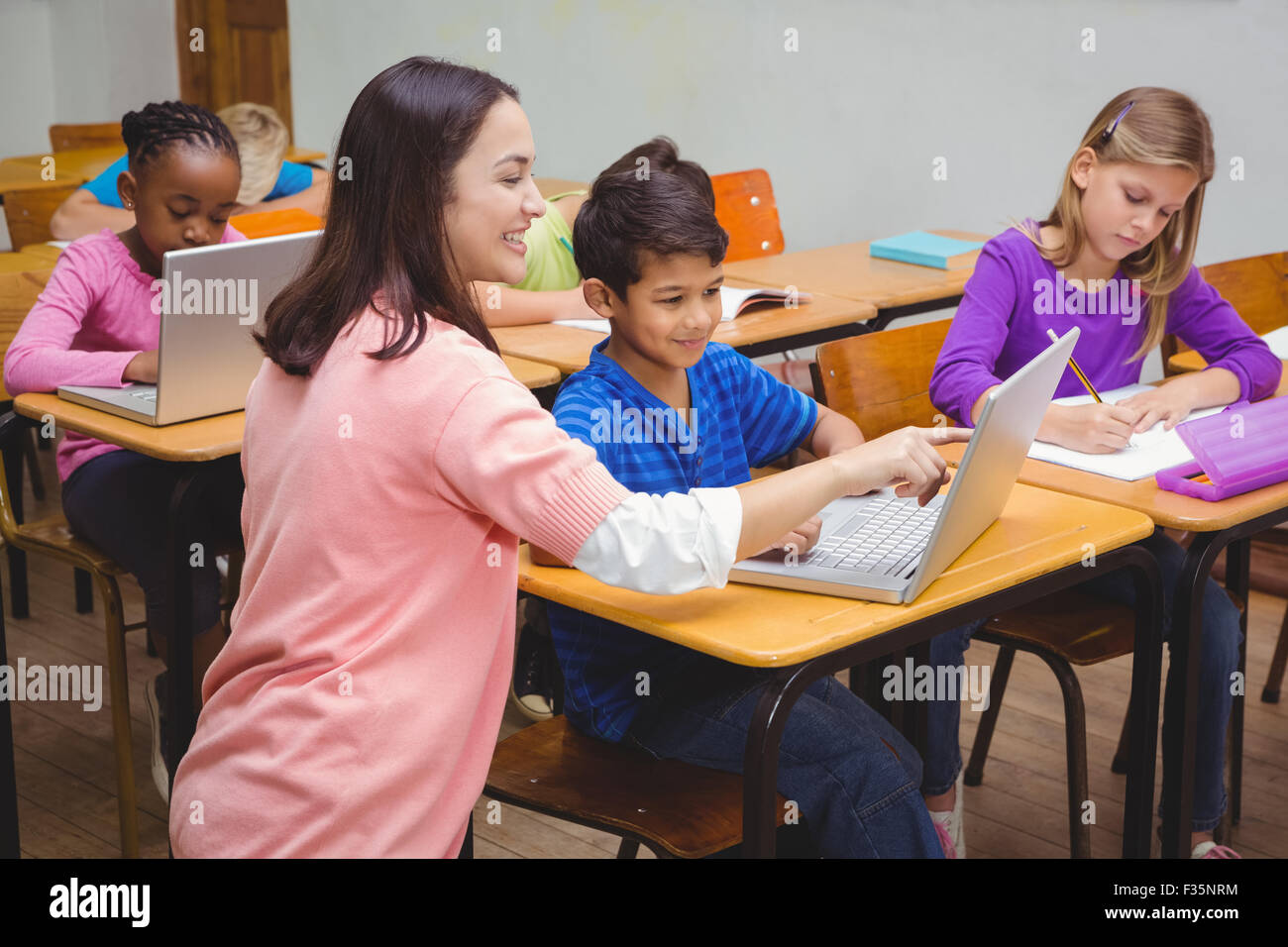 Happy teacher using laptop with student Stock Photo - Alamy