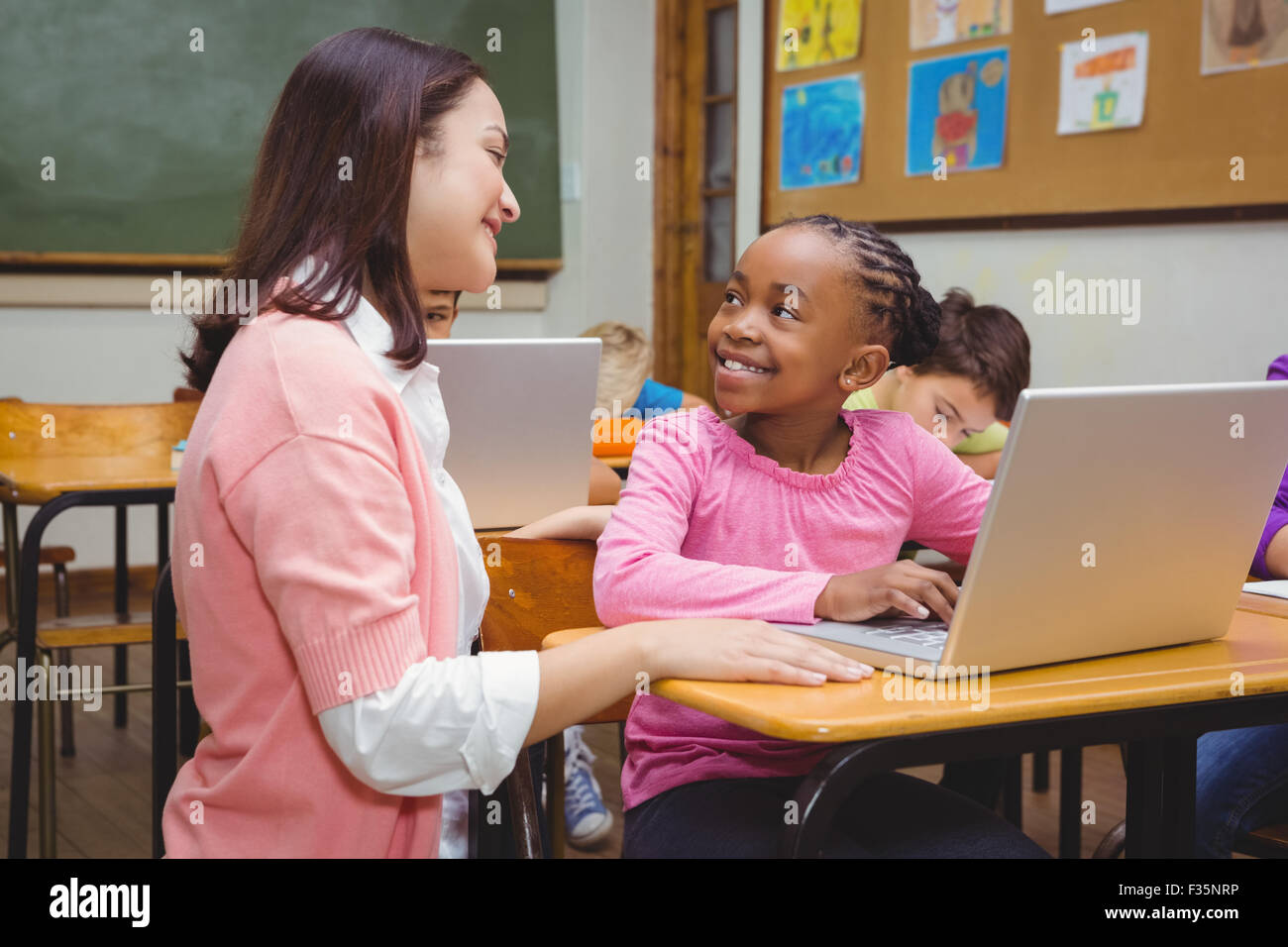 Happy teacher using laptop with student Stock Photo - Alamy