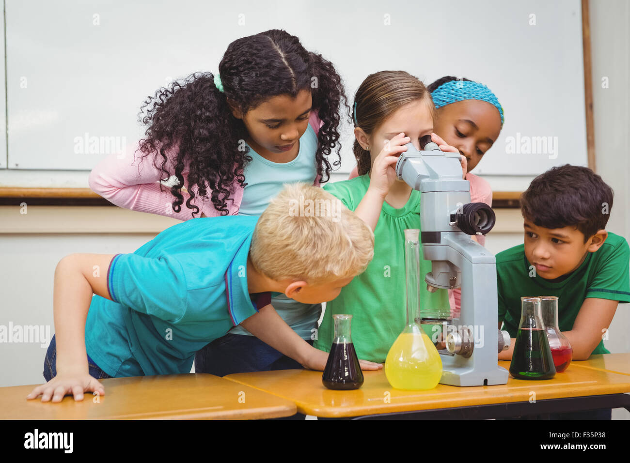 Students using science beakers and a microscope Stock Photo - Alamy