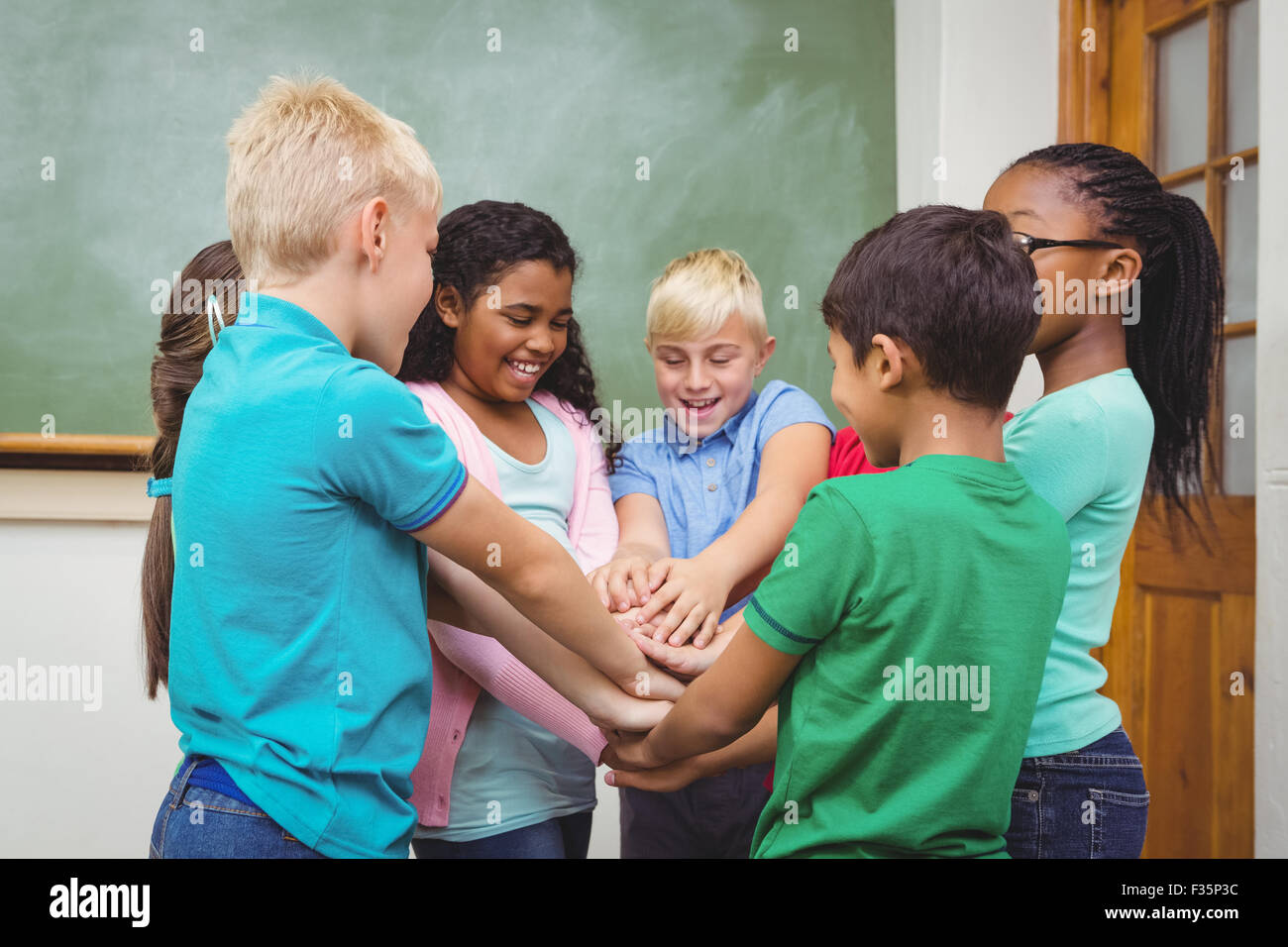 Students putting hands together Stock Photo - Alamy